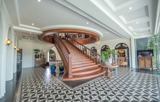 Uma imponente escadaria em espiral em um hall amplo, com piso estampado e decoração elegante.