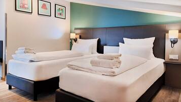 Quarto de hotel com duas camas, uma parede em tom de verde-água e luminárias fixadas na parede.