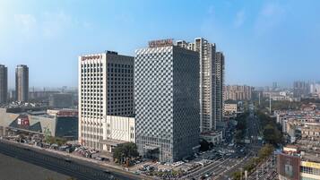 Paisagem urbana com edifícios modernos altos, um cruzamento movimentado e céu claro.