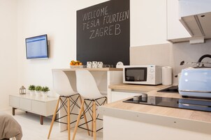 Cozinha moderna com quadro negro, micro-ondas, chaleira e área de refeições com cadeiras.