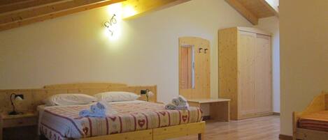 Quarto com cama de madeira, mesa de cabeceira, escrivaninha e guarda-roupa.