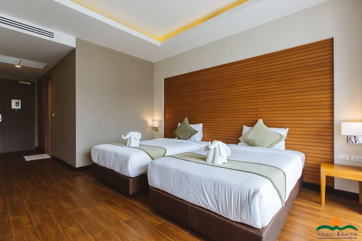 Quarto de hotel com duas camas, cabeceira de madeira e piso de madeira.