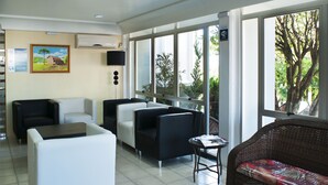 Um saguão de hotel com área de estar, um quadro na parede e uma grande janela com vista para árvores.