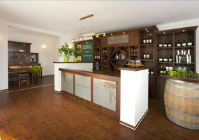 Uma área de bar com prateleiras de madeira, um balcão e um grande barril.