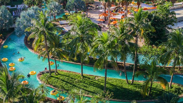 Resort com várias piscinas, palmeiras e áreas de estar ao ar livre.