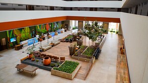 Um hall amplo com área de estar, plantas em vasos e um grande mural.