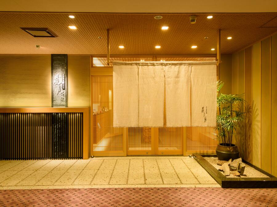 Uma área de recepção com balcão de madeira, um tradicional painel japonês shoji e uma planta em vaso.