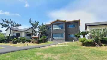 Uma casa moderna de dois andares, com janelas amplas, um caminho de entrada pavimentado e um gramado bem cuidado.