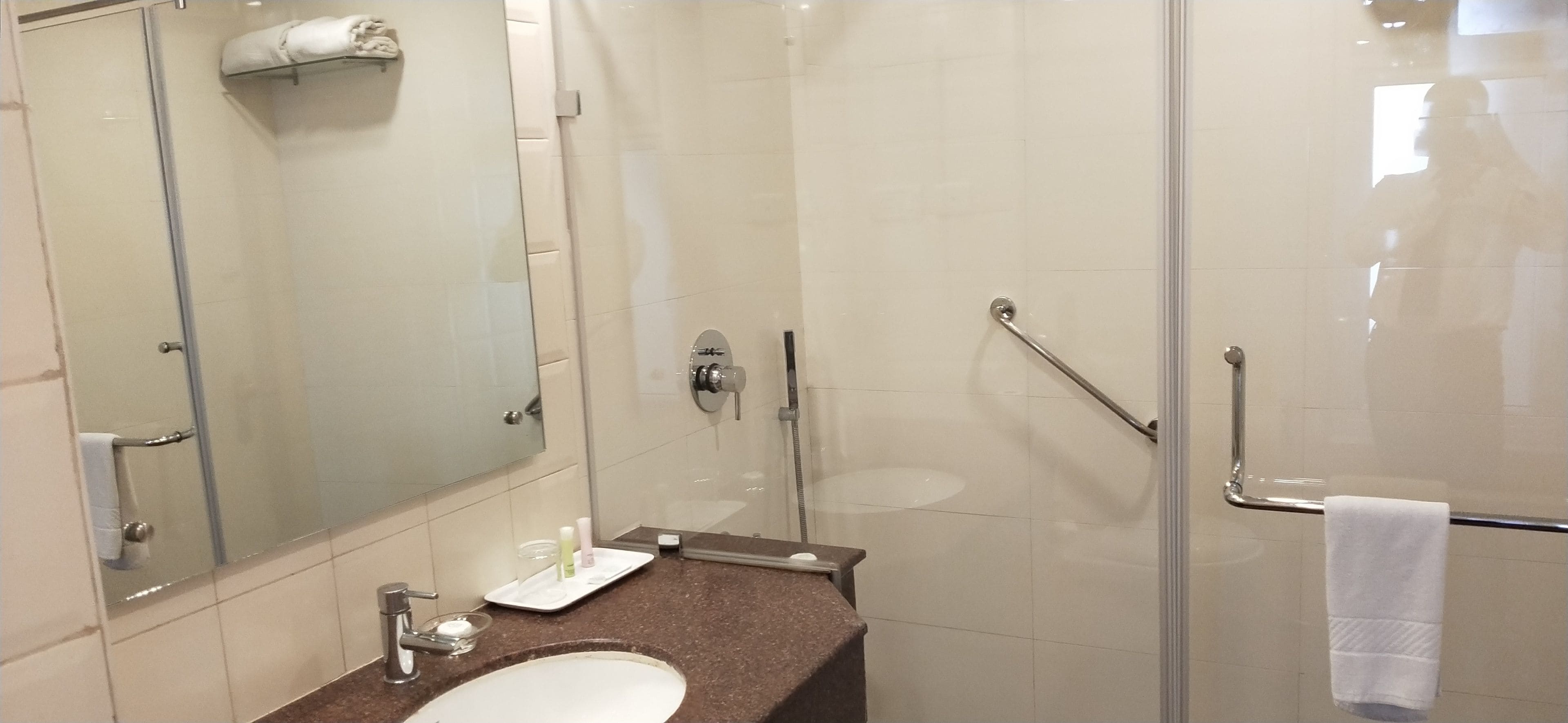 Uma casa de banho moderna com cabine de duche em vidro, toucador com lavatório e espelho.