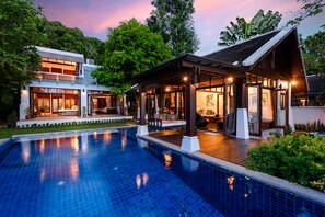 Uma casa moderna com piscina, varanda coberta e um jardim bem cuidado.