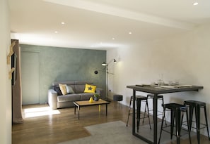 Uma sala de estar moderna com sofá, mesa de centro e um espaço de jantar com banquetas.