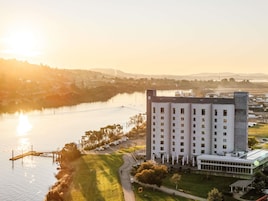 Um hotel com um edifício grande, estacionamento e um corpo de água.