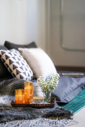 Uma cama com um cobertor estampado, um tabuleiro com velas e um pequeno vaso com flores.
