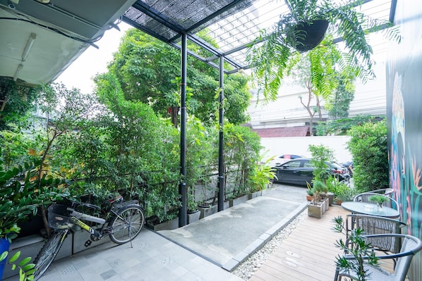 Uma área externa coberta com uma bicicleta, plantas em vasos e um espaço para sentar.