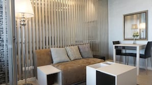 Quarto moderno com sofá, escrivaninha e cadeira. Há uma luminária e um espelho na parede.