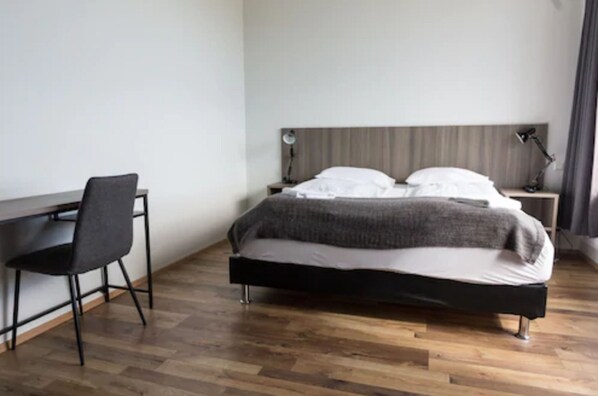 Quarto de hotel moderno com uma cama, uma escrivaninha e uma cadeira.