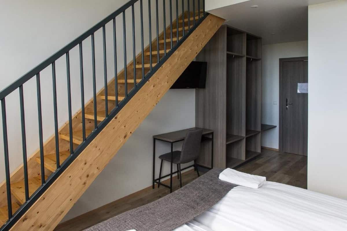 Quarto com escada de madeira, escrivaninha, cadeira, cama e estantes embutidas.