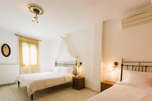 Quarto de hotel com duas camas, um radiador, uma janela com cortinas e um ar condicionado fixado na parede.