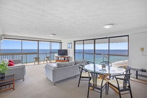 Varanda ampla com vista para o oceano, mobiliada com sofá, cadeiras e mesa de jantar.
