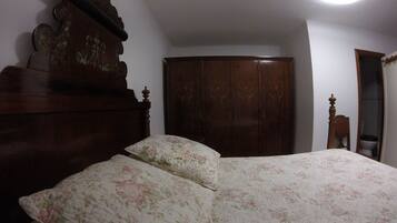 Quarto com cabeceira de madeira, guarda-roupa e cama com roupa de cama floral.