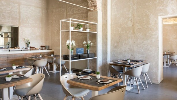 Interior de restaurante moderno, com paredes de tijolo aparente, prateleiras brancas e mobiliário minimalista.
