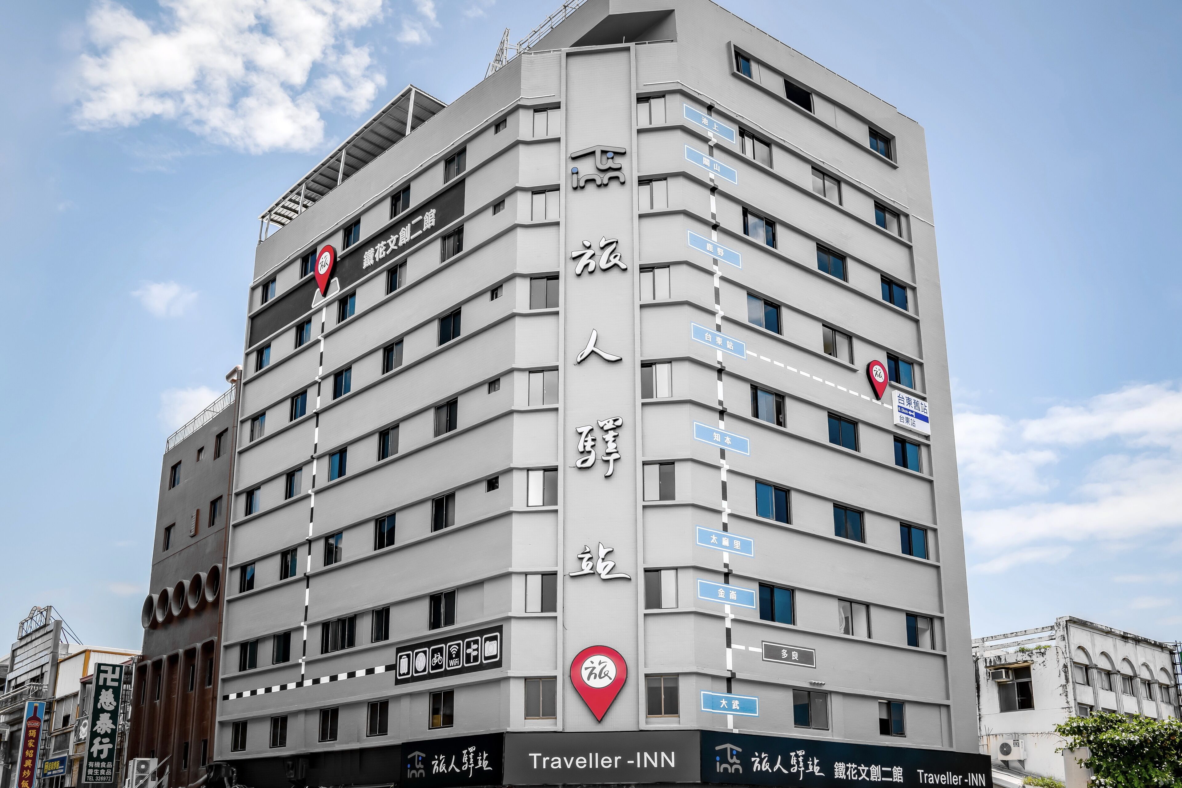 Um hotel de vários andares com design moderno, exibindo um logotipo marcante e sinalização que indica comodidades como restaurante e centro de negócios.