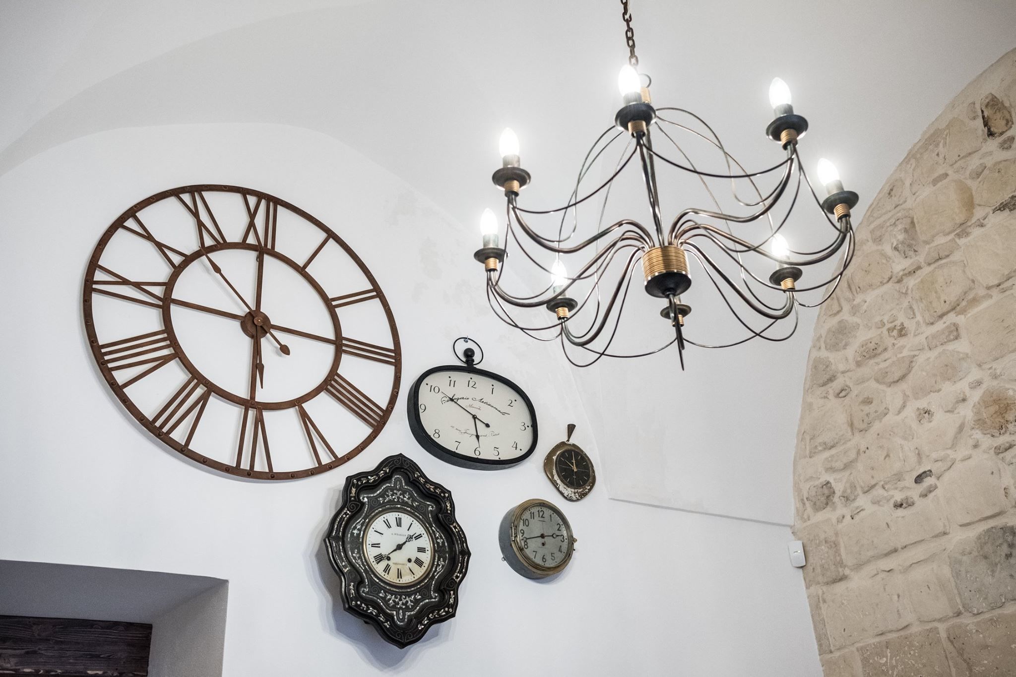 Um quarto com um relógio de parede grande, um relógio de parede menor e um candelabro.