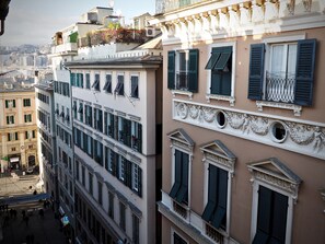 Um edifício de vários andares com varandas, detalhes arquitetônicos elaborados e vista da rua.