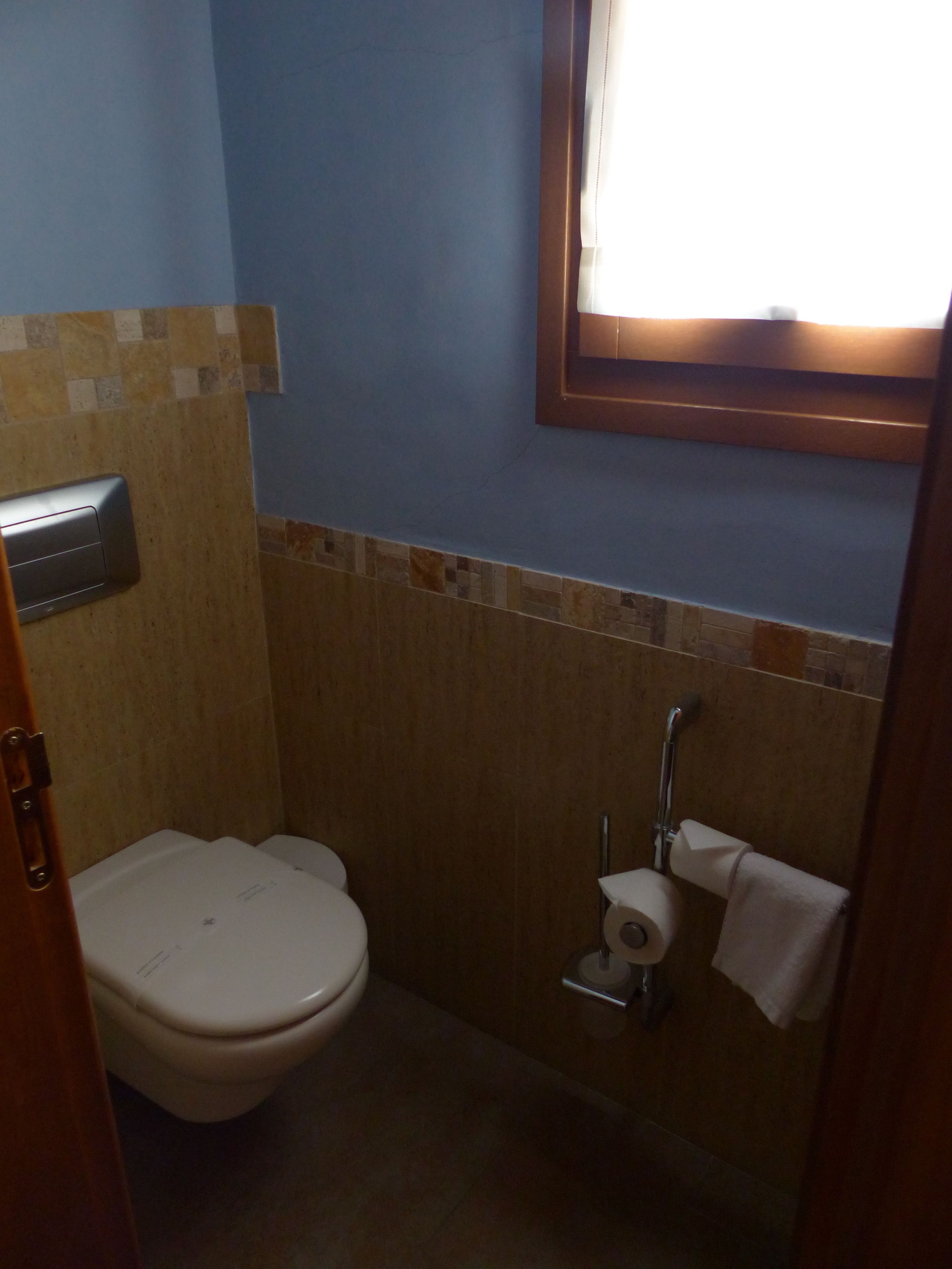 Casa de banho pequena com sanita, porta-toalhas e janela.