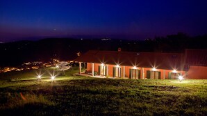 Um edifício com várias entradas iluminadas e um gramado bem iluminado à noite.