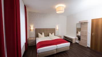 Quarto de hotel moderno com uma cama grande, mesas de cabeceira, um espelho e um guarda-roupa.