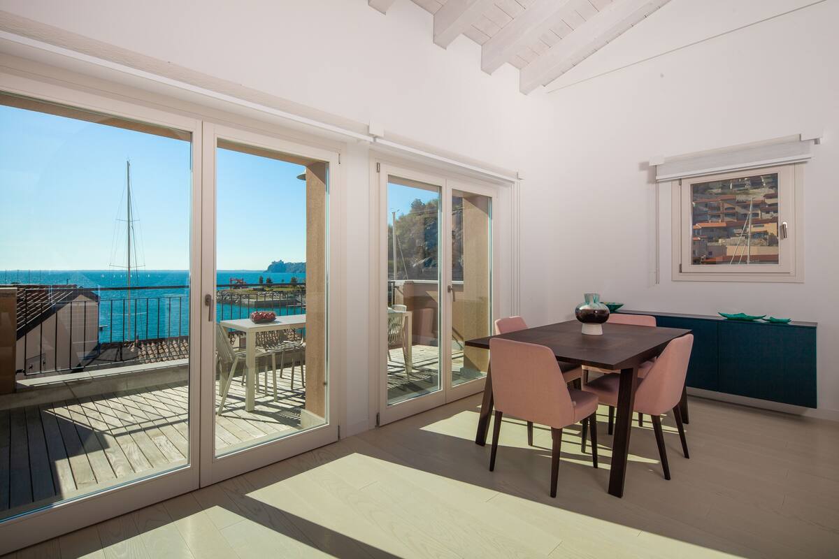 Quarto espaçoso com uma grande porta de vidro deslizante que dá para uma varanda com vista para o mar.