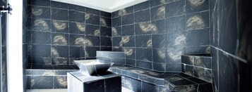 Casa de banho com azulejos de mármore escuro e uma sanita moderna.