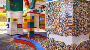 Uma área de recreação colorida com uma piscina de bolinhas e uma parede coberta por blocos empilhados.