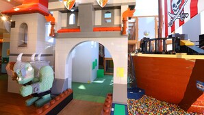 Um castelo LEGO com uma bandeira pirata, uma piscina de bolinhas e uma escada que leva a um nível superior.