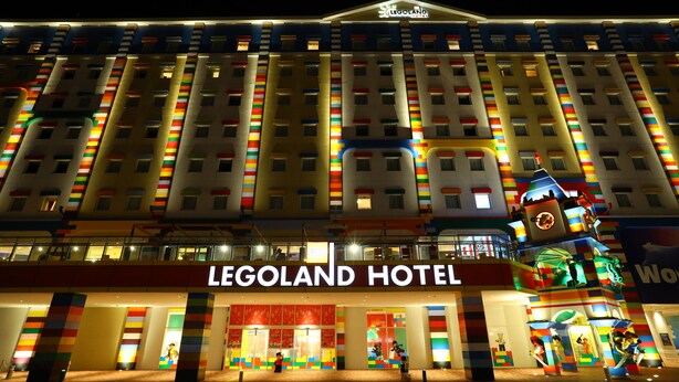 Exterior do Hotel Legoland, com fachada colorida e uma torre do relógio imponente.