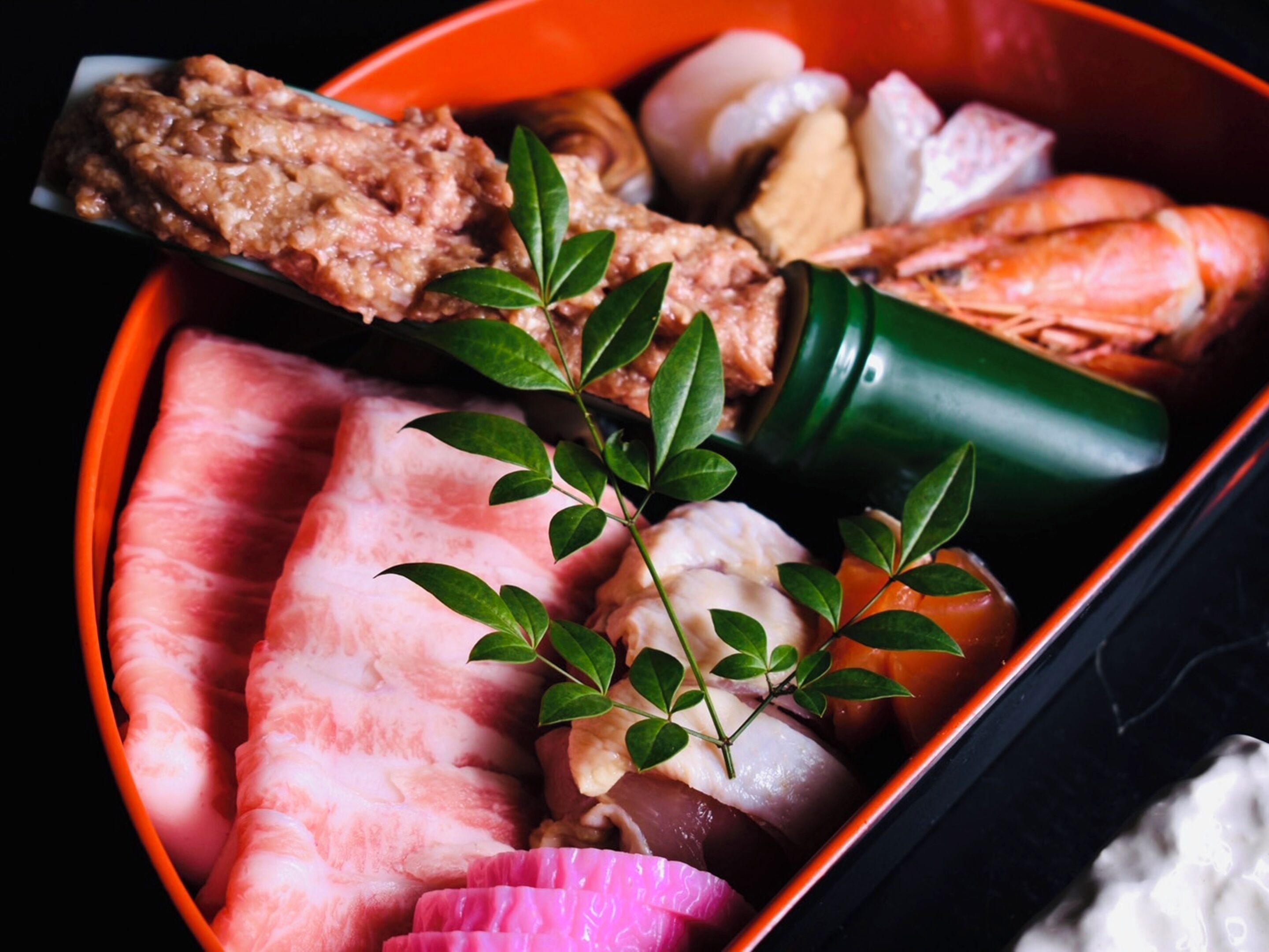 Uma lancheira bento com diversos alimentos, incluindo peixe, legumes e uma garrafa.