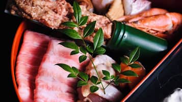 Uma lancheira bento com diversos alimentos, incluindo peixe, legumes e uma garrafa.