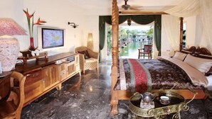 Quarto com cama, televisão, cómoda de madeira, secretária e vista para uma piscina.