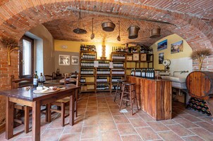 Um espaço de bar rústico com mobiliário de madeira, teto de tijolos e prateleiras cheias de garrafas.