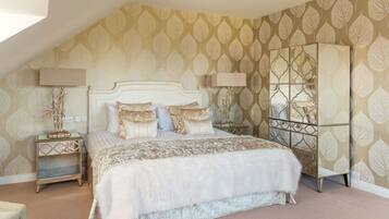 Quarto com uma cama grande, duas mesas de cabeceira, um espelho e papel de parede estampado.