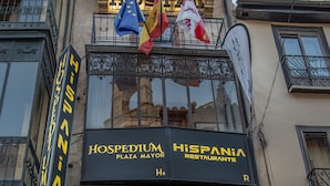 Um edifício com uma fachada exibindo a placa 'HOSPEDIUM' e 'HISPANIA RESTAURANTE'.