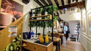 Uma área de recepção de hotel com um balcão de madeira, uma vitrine de vidro e uma placa indicando a recepção.