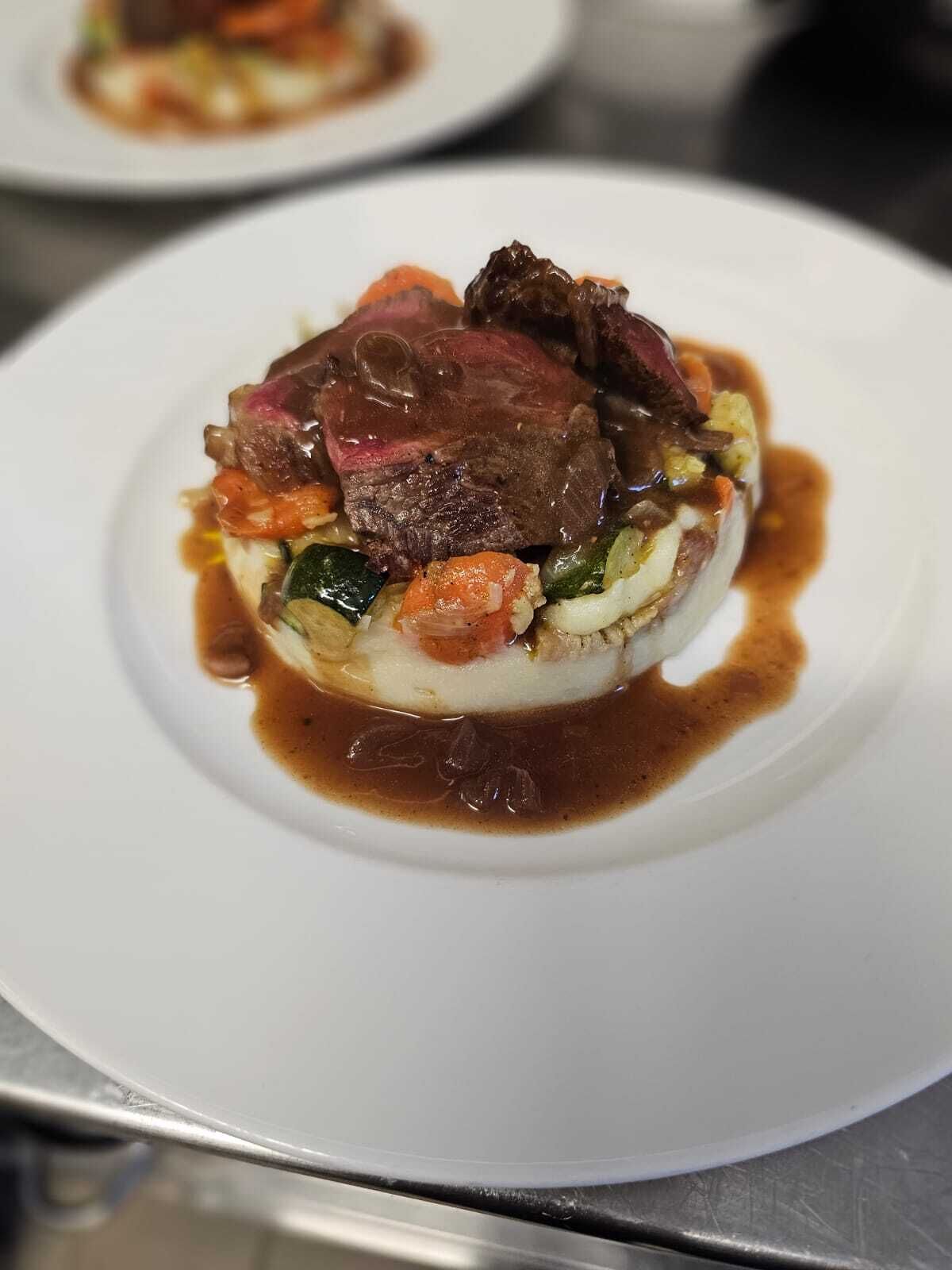 Prato com bife, legumes e molho.