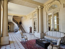 Um amplo hall com piso de mármore, uma escadaria, um sofá e uma mesinha de centro.