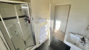 Uma casa de banho moderna com chuveiro envidraçado, lavatório branco e porta-toalhas.
