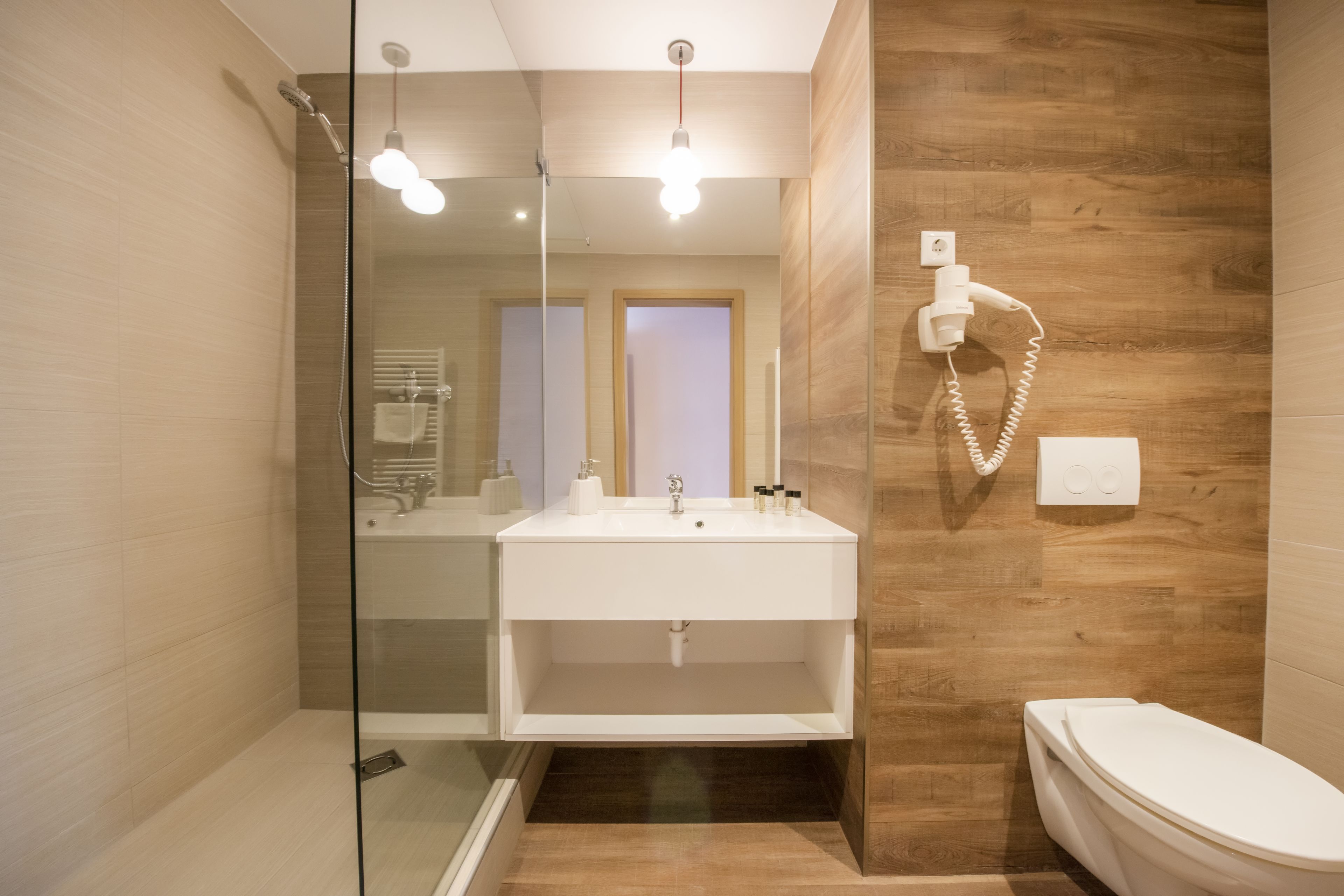 Um banheiro moderno com box de vidro, pia branca e vaso sanitário.