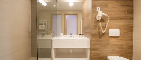 Um banheiro moderno com box de vidro, pia branca e vaso sanitário.
