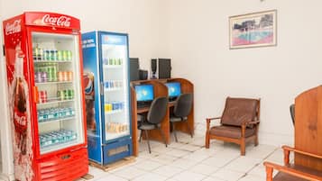 Quarto com geladeira Coca-Cola, geladeira Pepsi, dois computadores e uma cadeira de madeira.