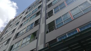 Um edifício de vários andares com design arquitetônico moderno, com uma série de varandas e janelas amplas.